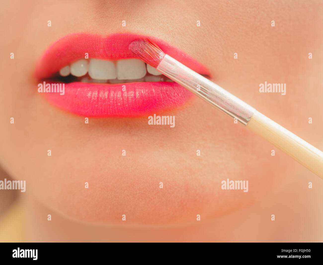 Close up of woman applying lipstick with brush on lips. Girl ...