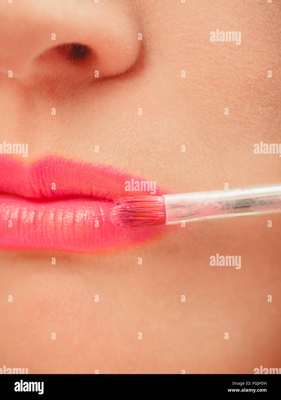 Close up of woman applying lipstick with brush on lips. Girl ...