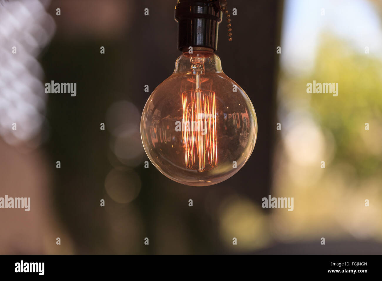 Ornamental light bulb lit up and hanging from the ceiling with a modern ...