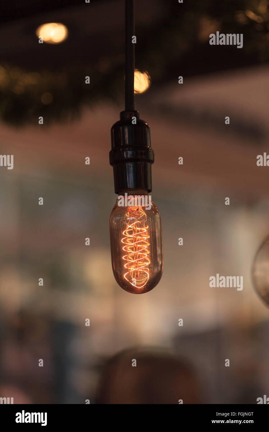 Ornamental light bulb lit up and hanging from the ceiling with a modern ...