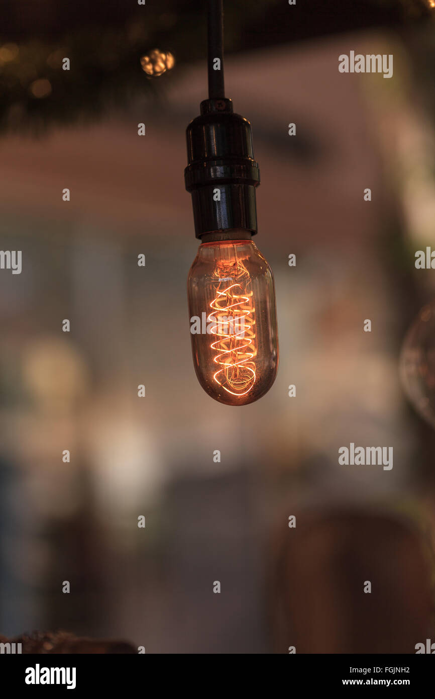 Ornamental light bulb lit up and hanging from the ceiling with a modern ...