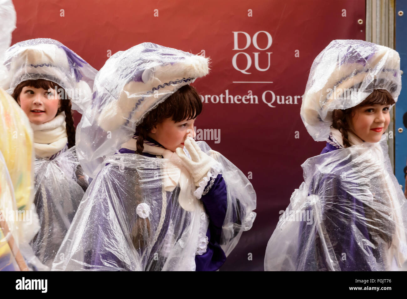 three baby majorettes wrapped up against rain at Carnival parade ...