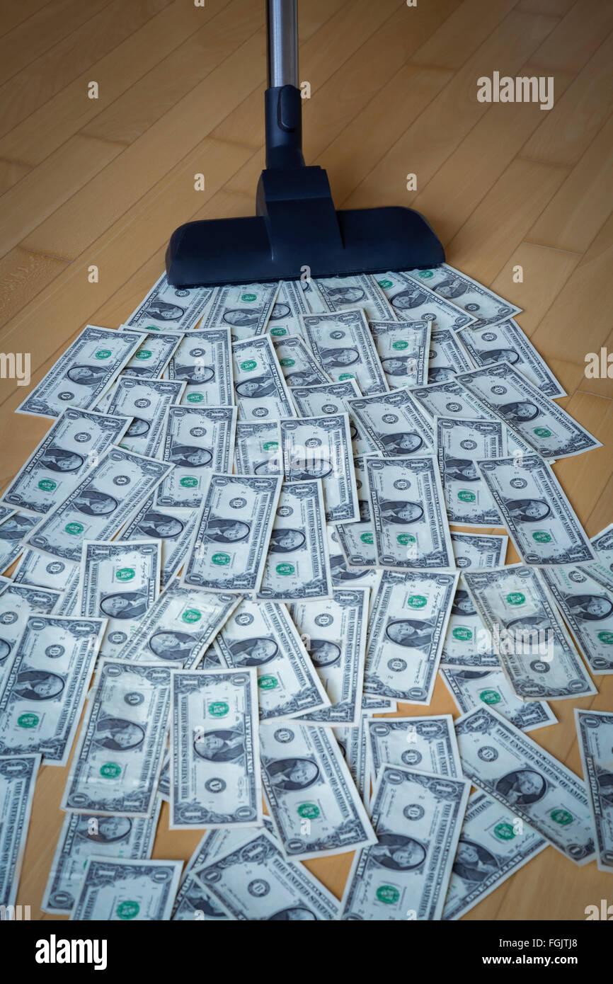 A Vacuum cleaner soaking in dollar notes on a wooden floor Stock Photo ...