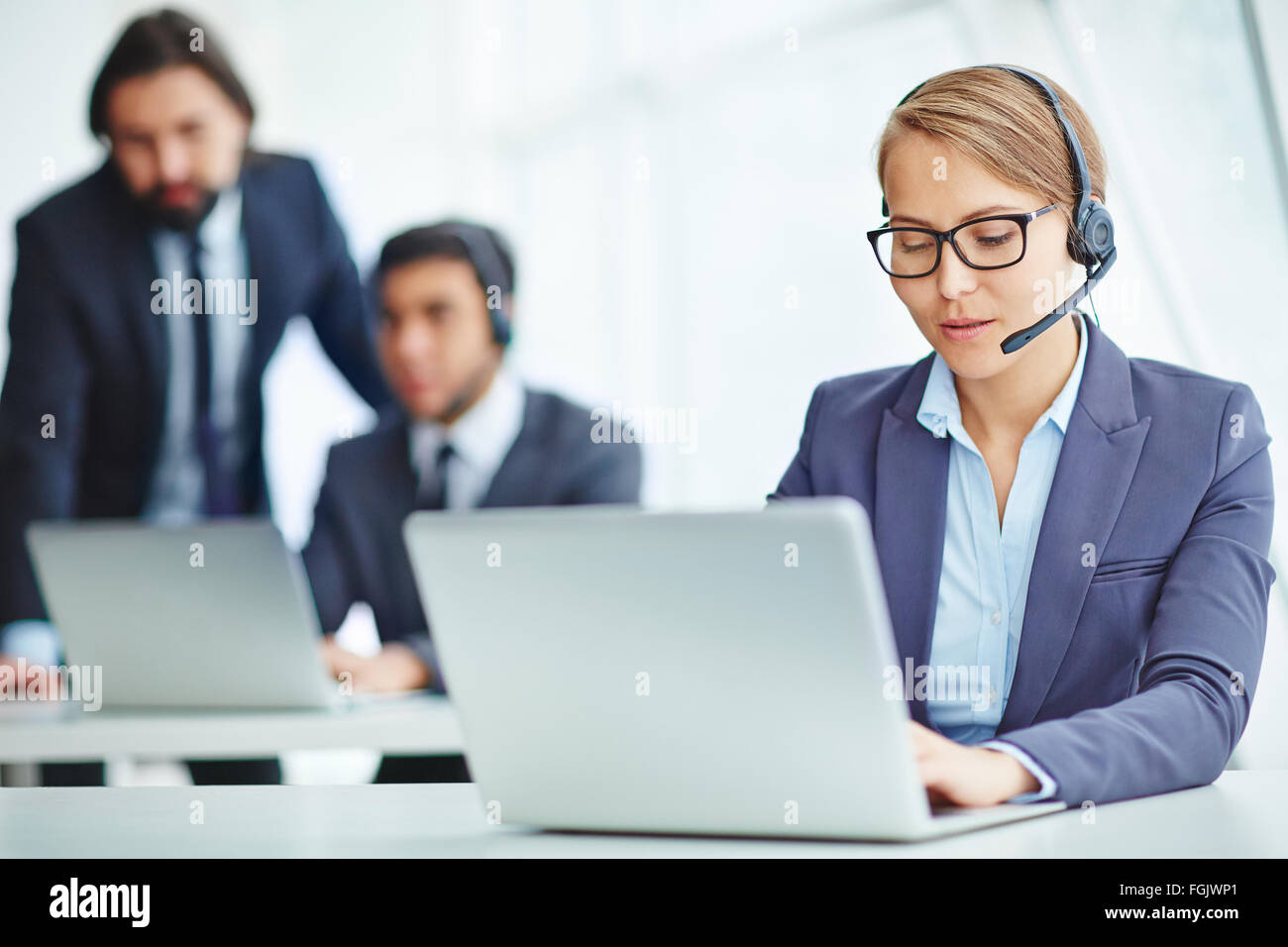 Busy operator with headset typing on laptop Stock Photo - Alamy