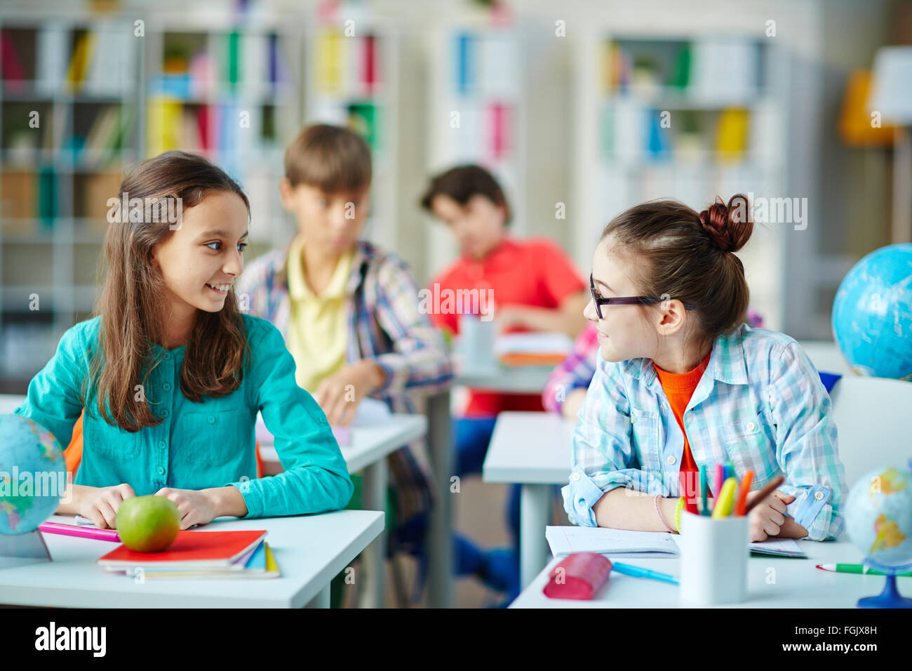 Friendly girls chatting in classroom at break Stock Photo - Alamy