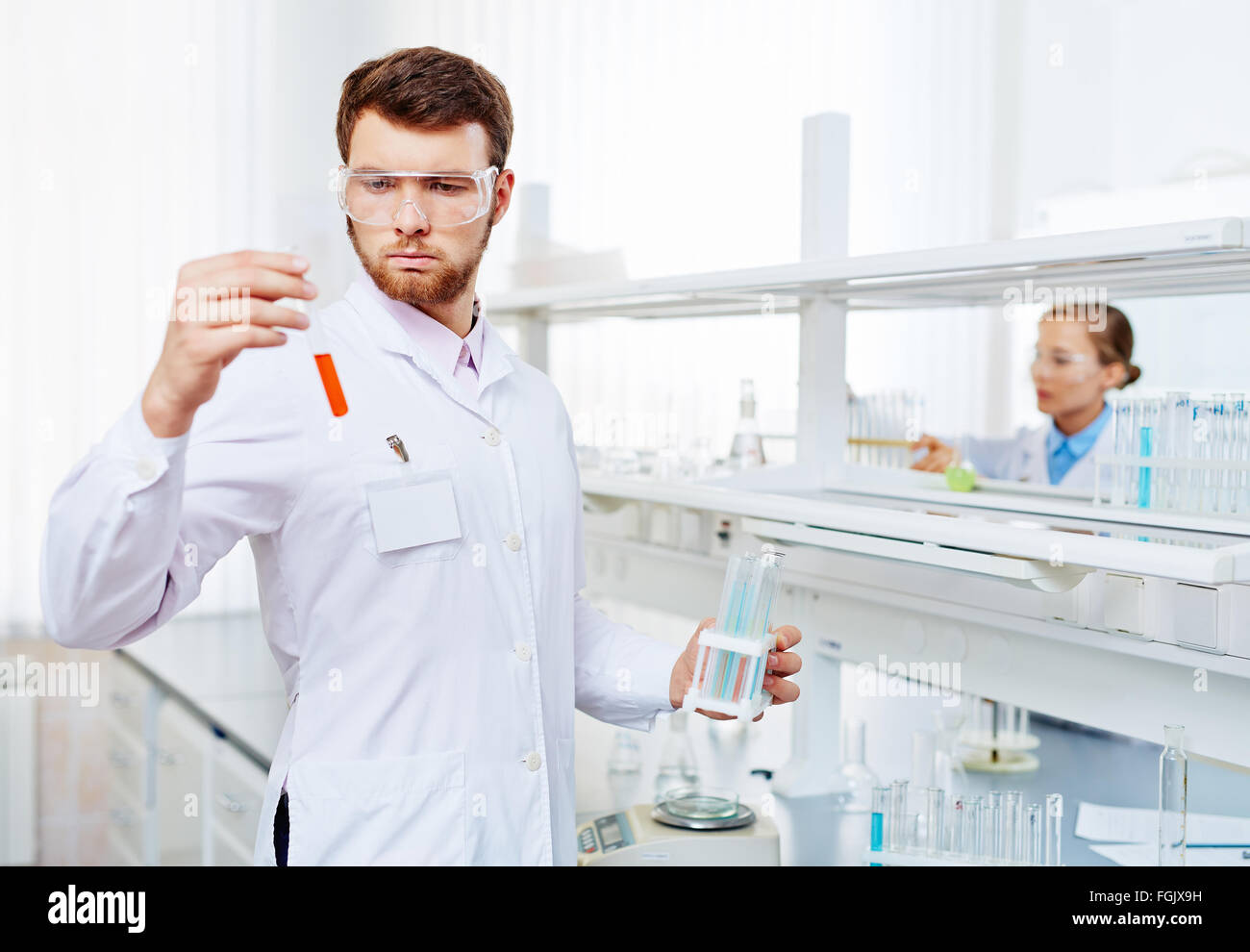 Young chemist looking at fluid substance in flask Stock Photo - Alamy