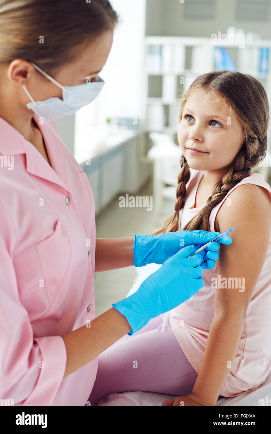 Cute girl looking at nurse during injection in hospital Stock Photo - Alamy