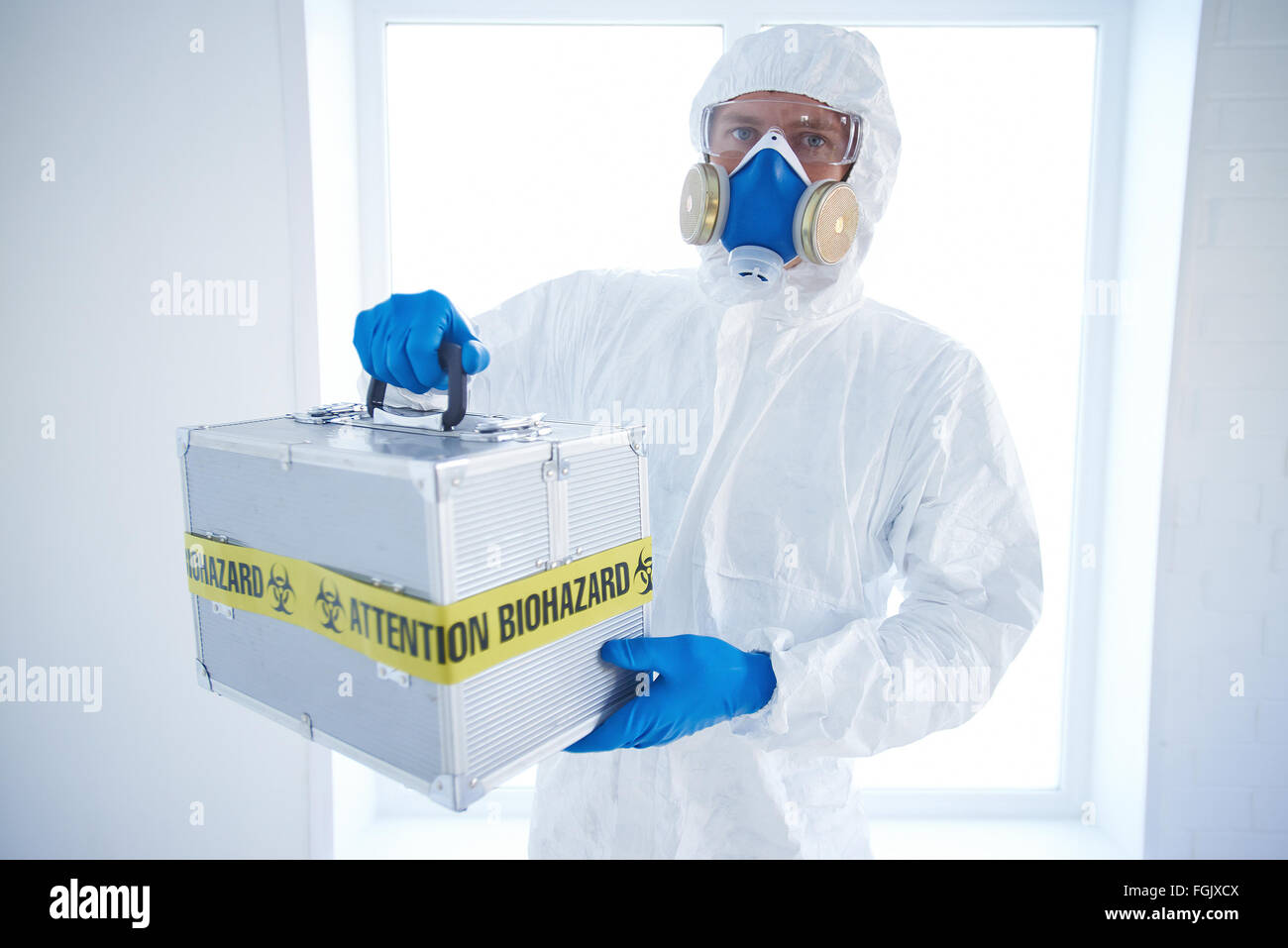 Man in protective overall holding case with biohazard symbol Stock ...
