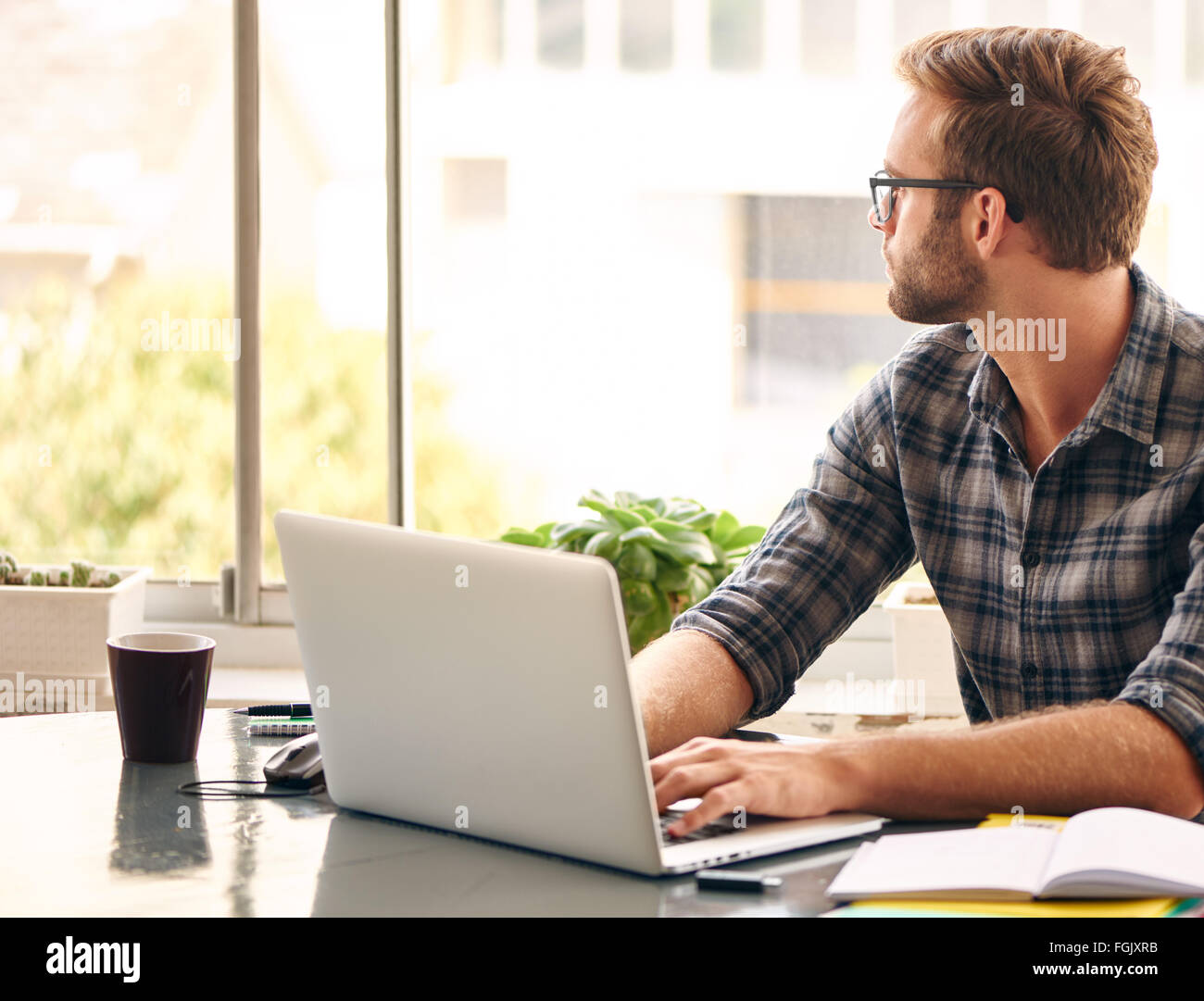 Young entrepreneur looking out the window in thought Stock Photo - Alamy