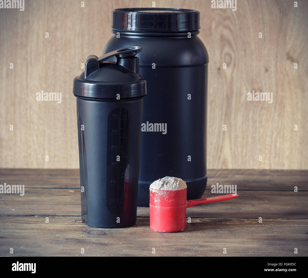 Whey protein powder in scoop with vitamins and plastic shaker on wooden ...