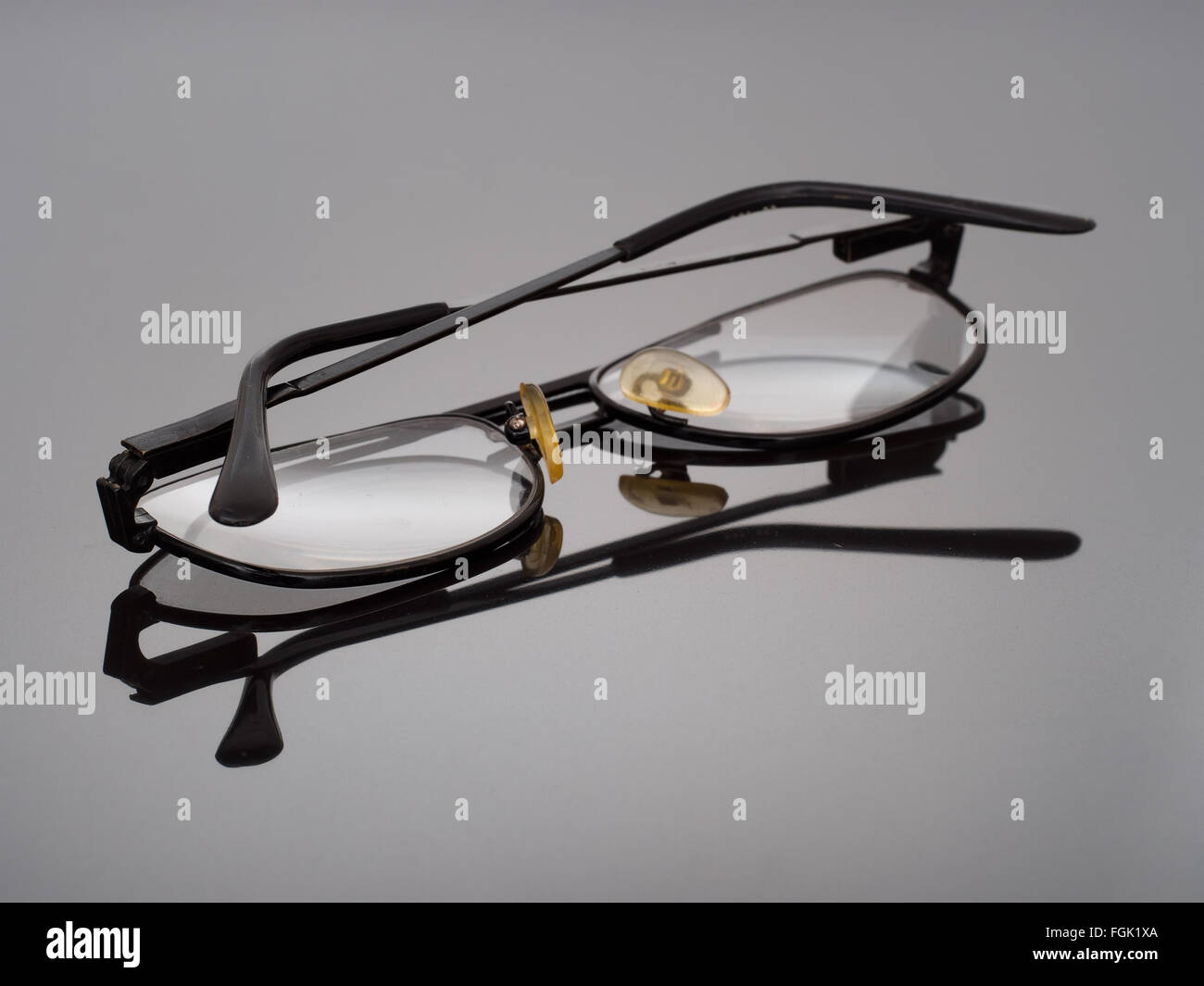 Reading glasses reflected on dark textured background Stock Photo - Alamy