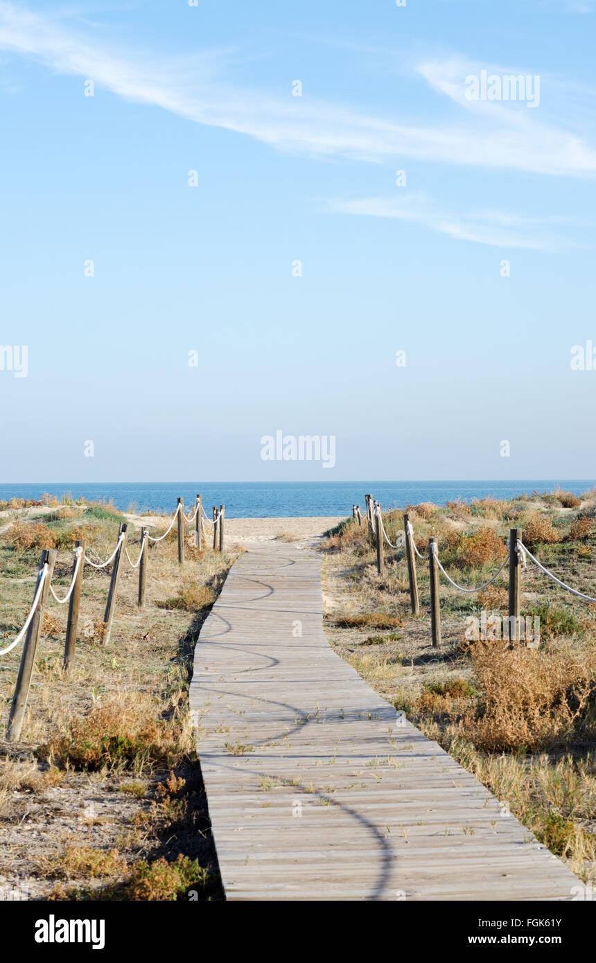 Wooden boardwalk with railing leading down to a beach and to the ocean ...