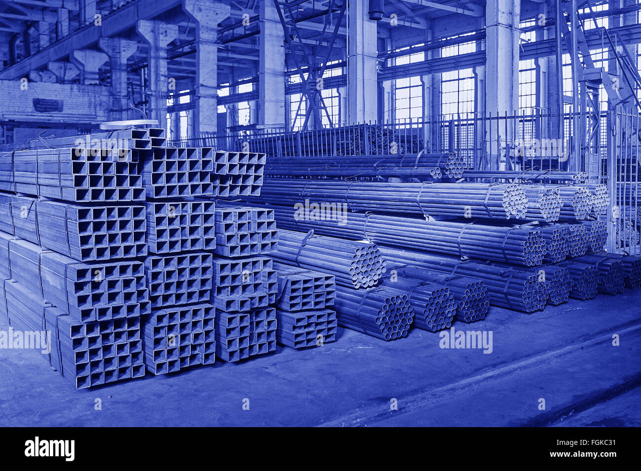 Metal pipes in a warehouse. Stacks of new square and round steel pipe ...