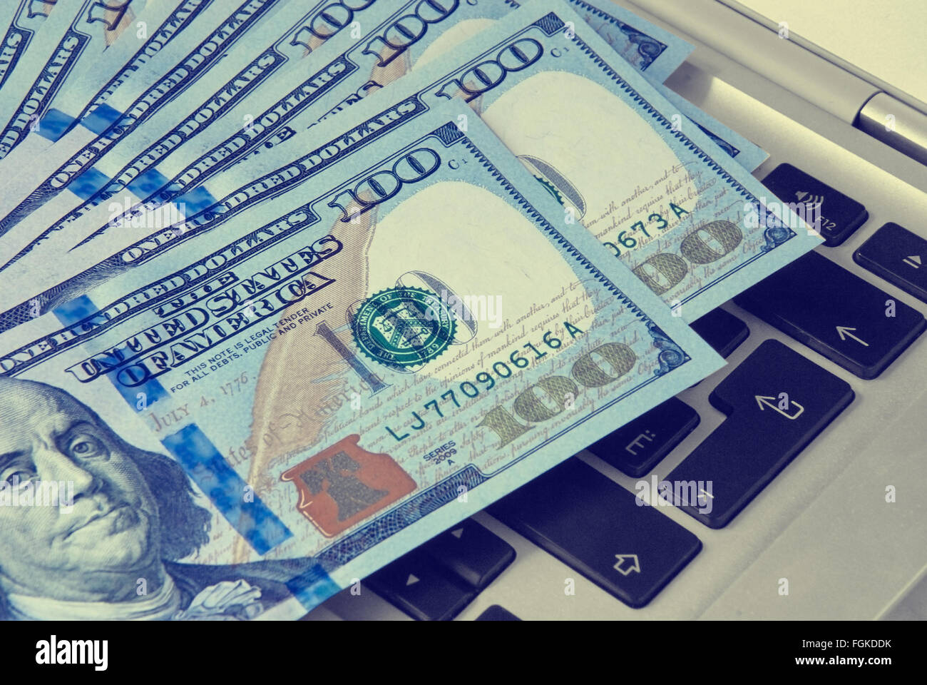 hundred-dollar bills on keyboard. Silver metal laptop. Toned image ...