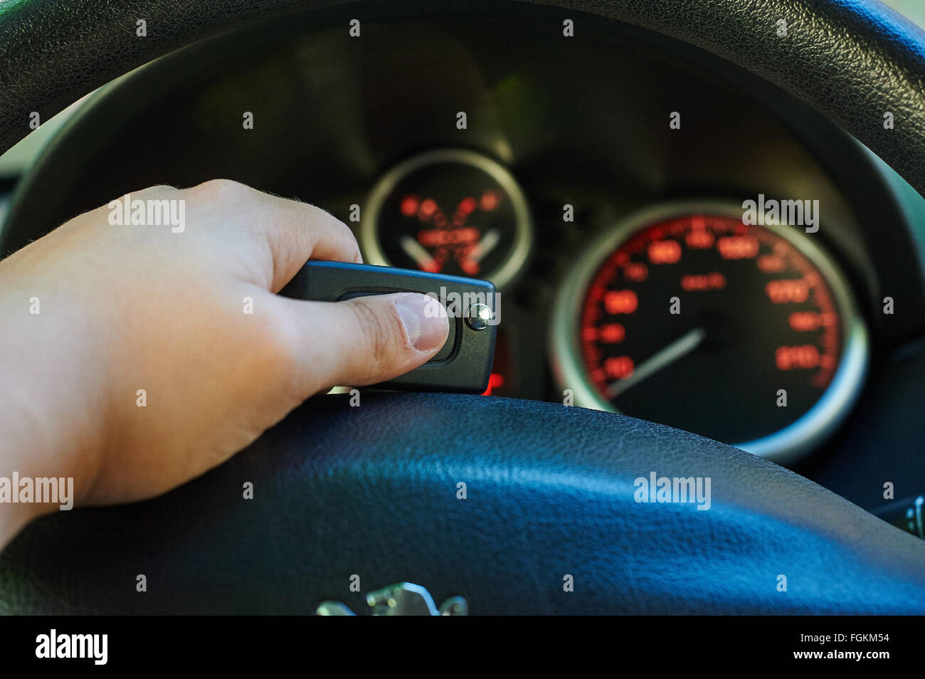 Man driver hand holding car key. Orange glowing meters with a red ...