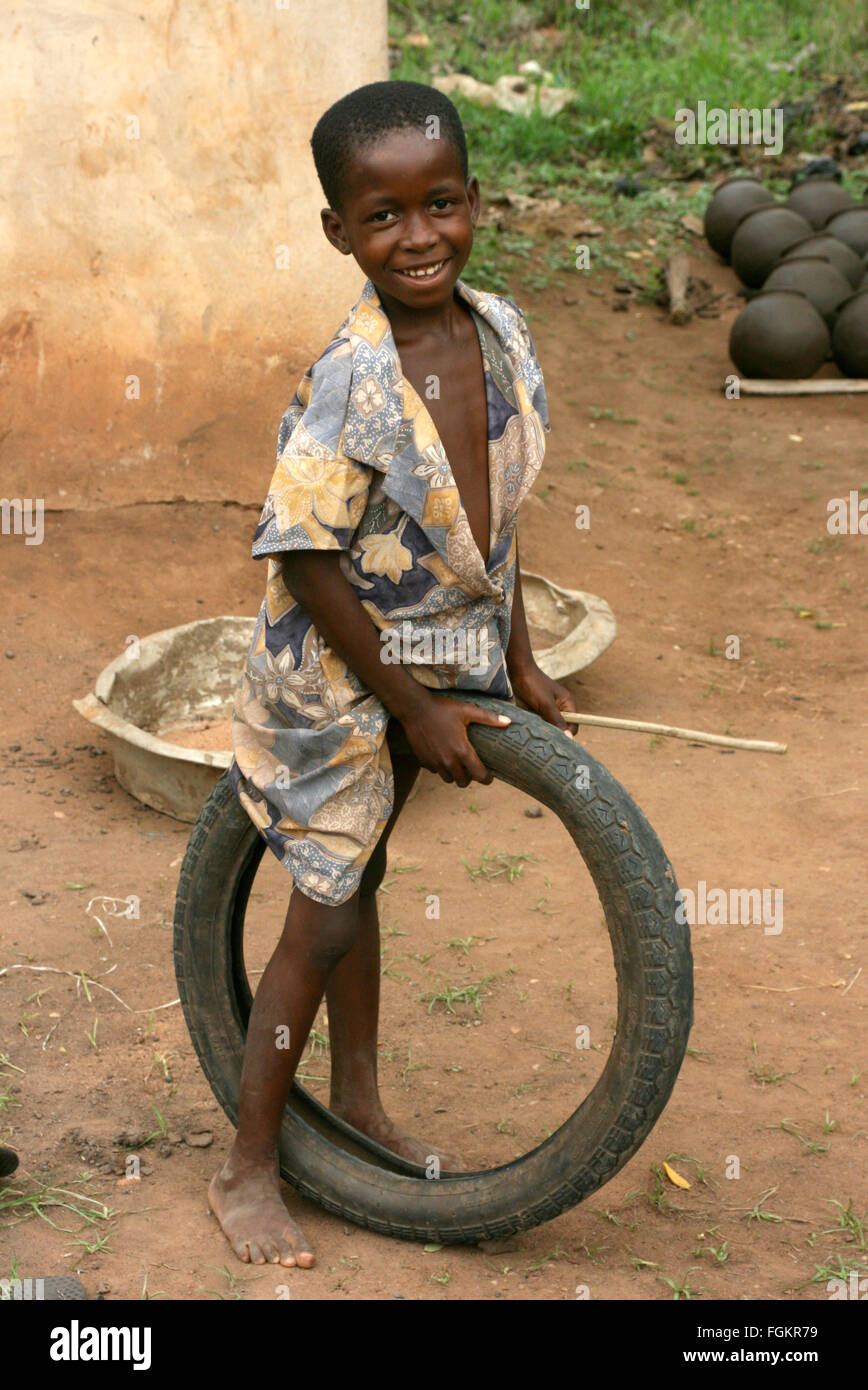 Smiling African boy rolls stick and tire in Benin, West Africa Stock ...