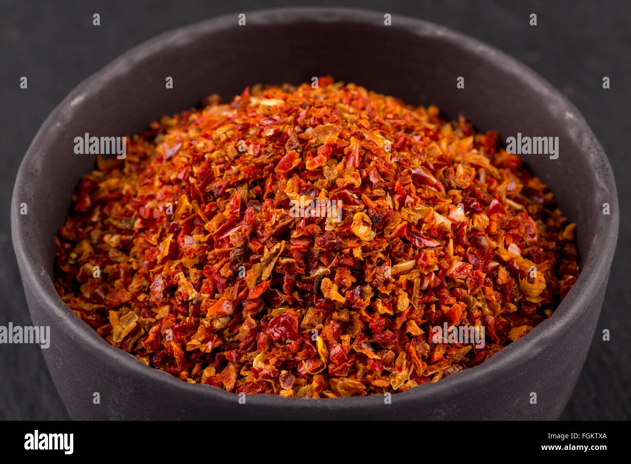 Crushed red chili pepper in stone bowl on dark background Stock Photo ...