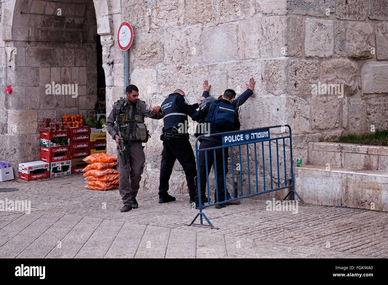 Israeli policemen body-check a young Palestinian man at the entrance of ...