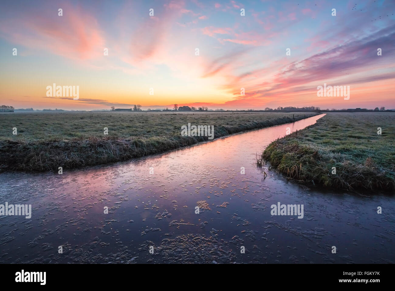 Beautiful sunrise at a frozen meadow with a little ground fog above ...