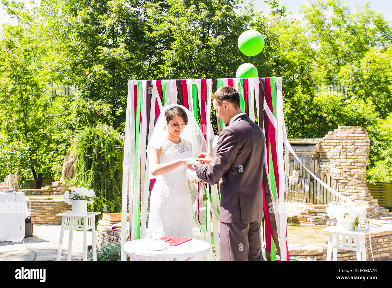 Groom giving an engagement ring to his bride under the arch. Wedding ...