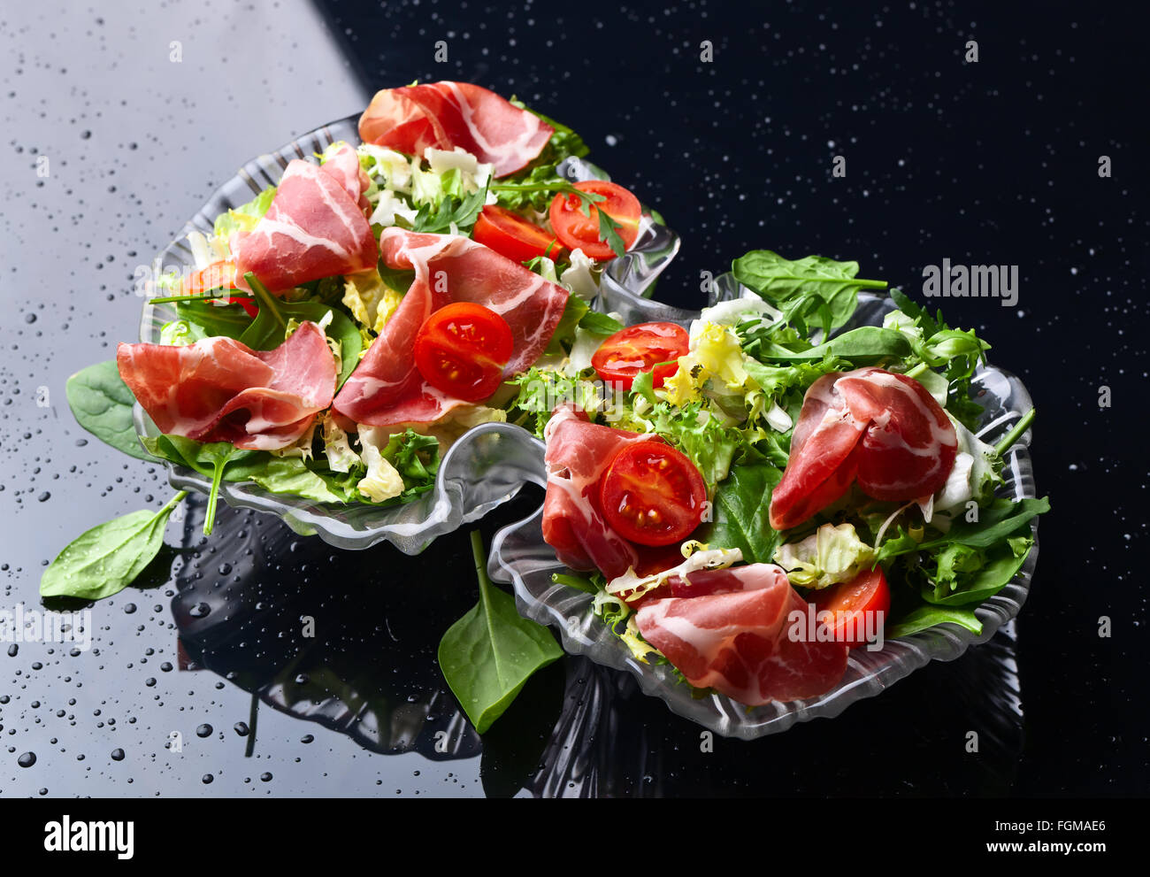 green salad with jamon on a black background Stock Photo - Alamy