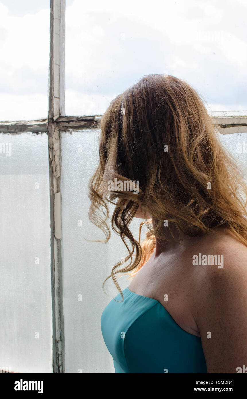 Woman looking out of a window Stock Photo - Alamy