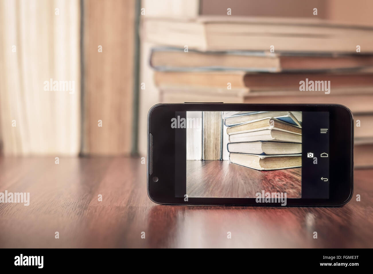 Taking picture of stack of old books with smartphone, looking at books ...