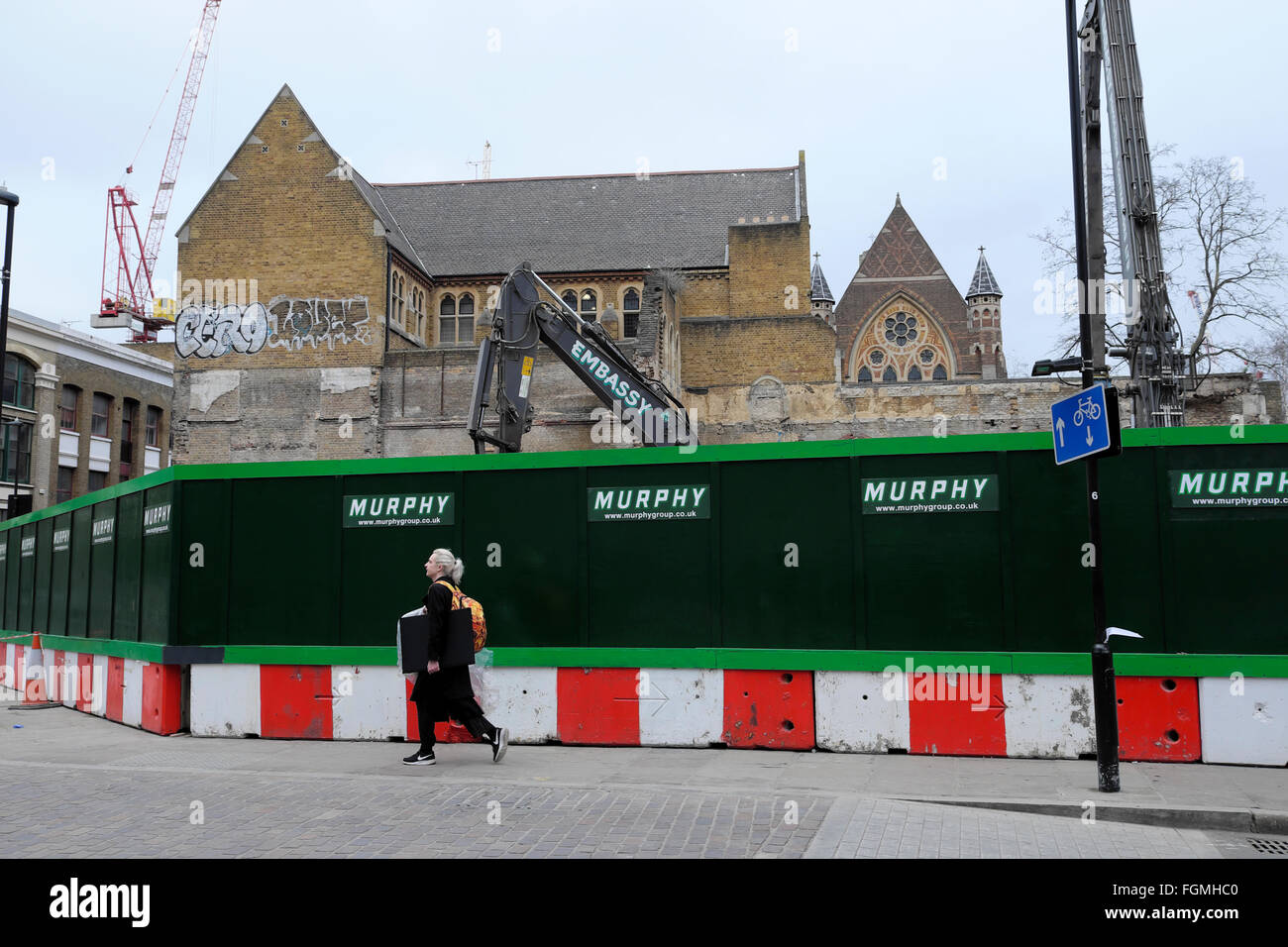 An art student walking past Murphy construction site cranes and logo on ...