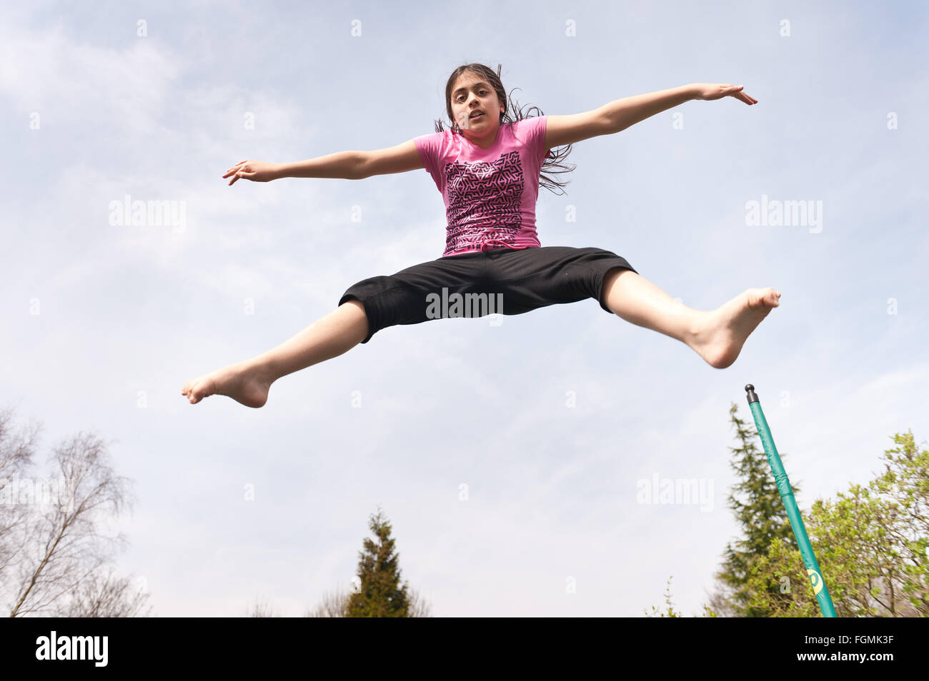 Teenager jumping high in the air bouncing off a trampoline doing ...