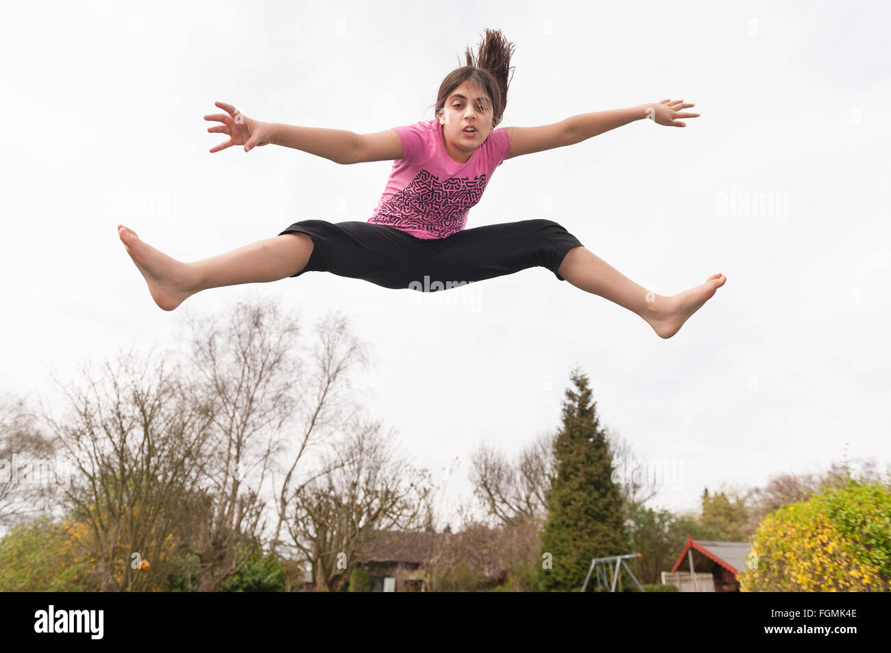Teenager jumping high in the air bouncing off a trampoline doing ...