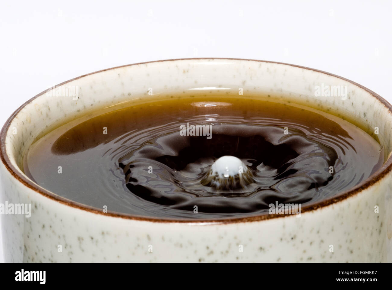 milk drop falling into cup black coffee mixing and splashing drop ...