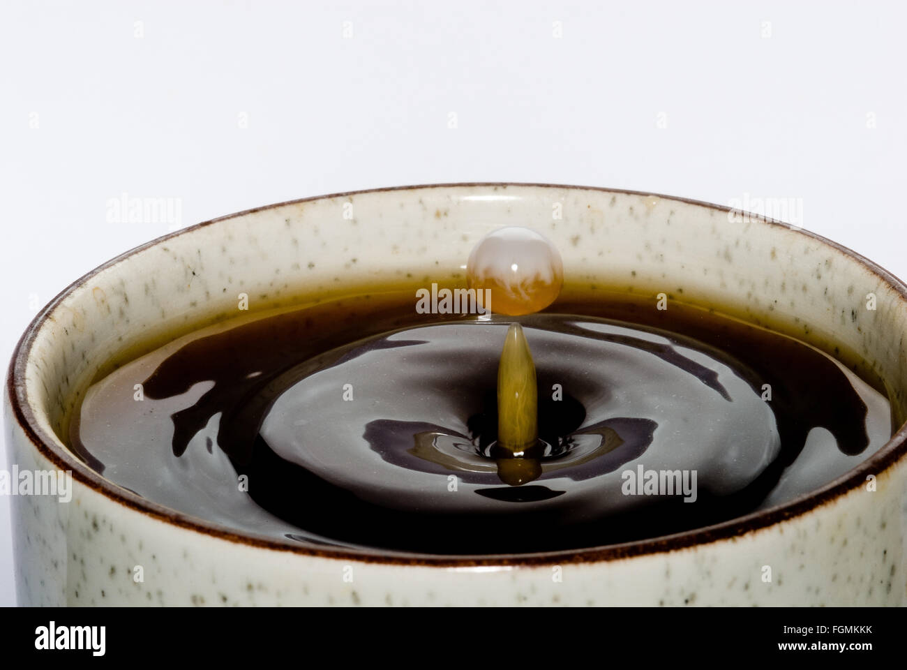 milk drop falling into cup black coffee mixing and splashing drop ...
