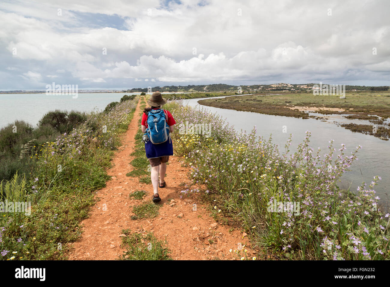 Person walking the trail around the Alvor Nature Reserve lagoon ...