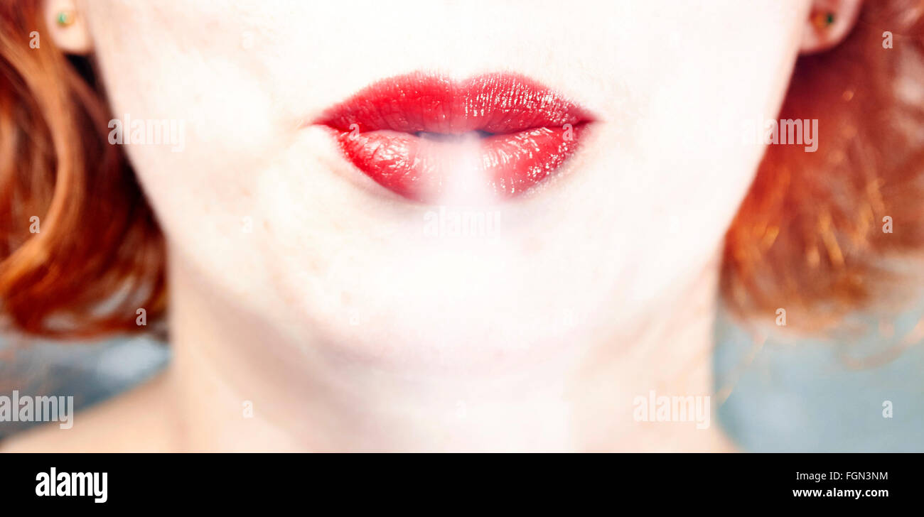 Young woman with red lips blowing out cigarette smoke Stock Photo - Alamy