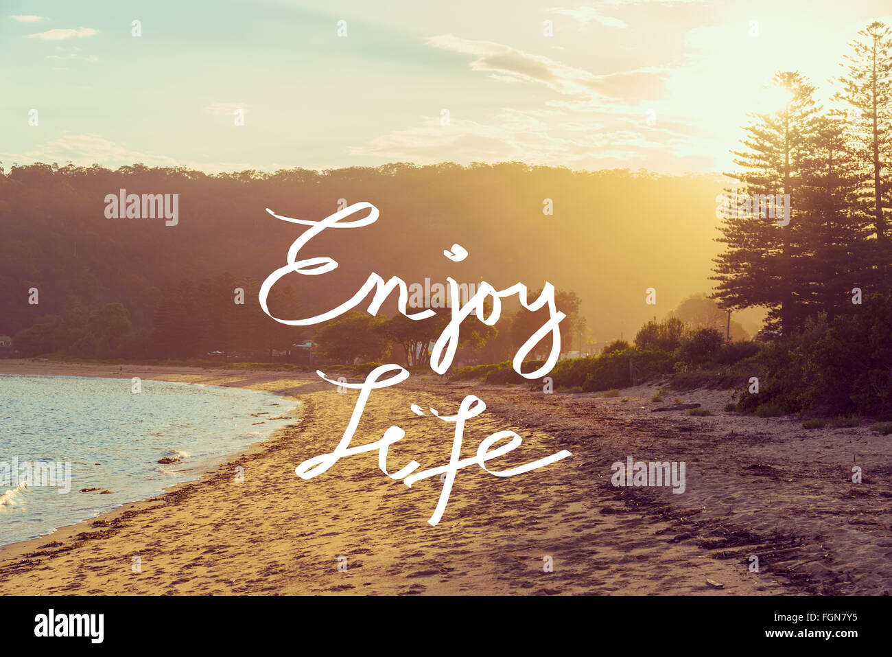 Handwritten text over sunset calm sunny beach background, ENJOY LIFE ...