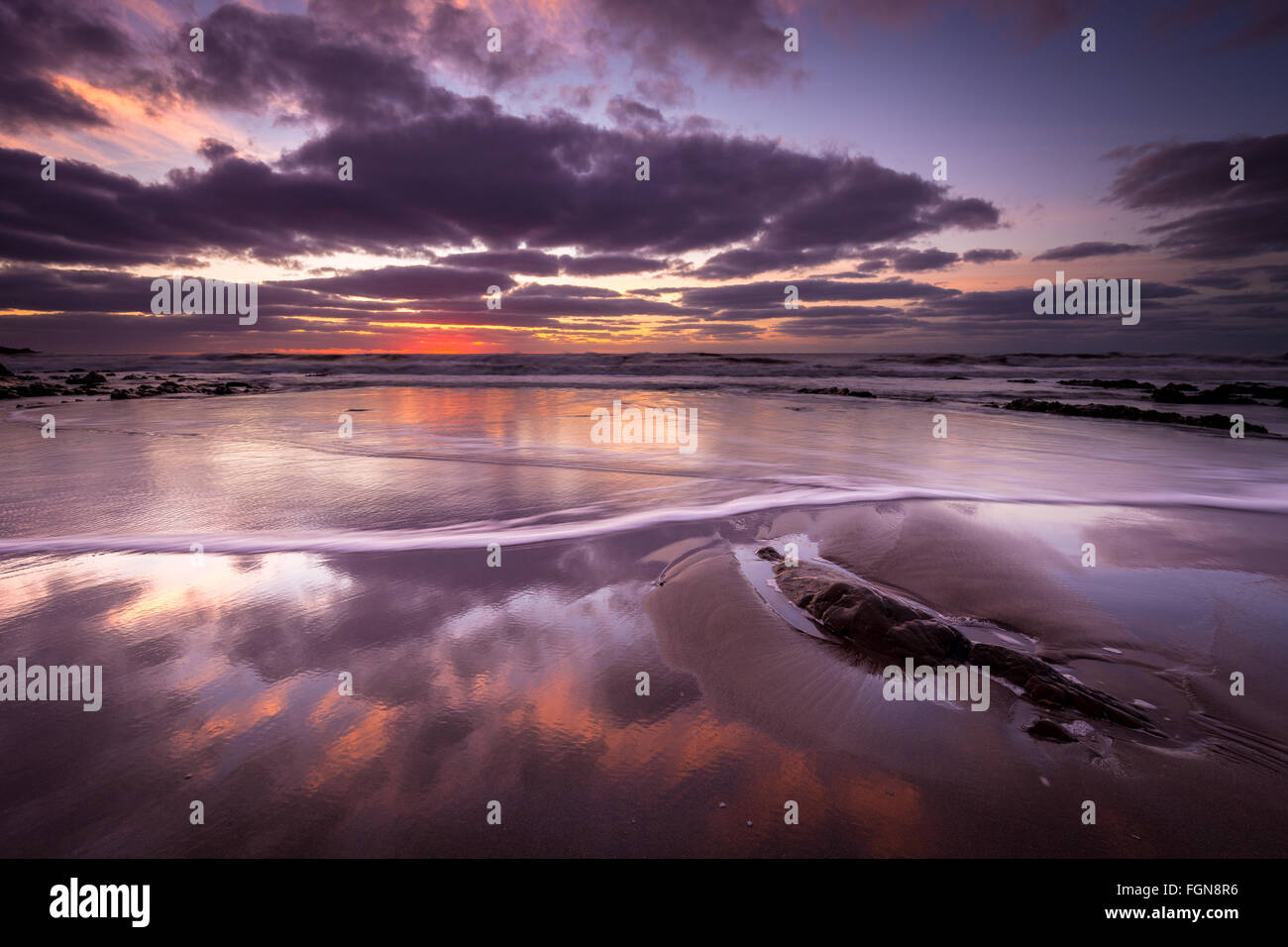 Sunset at Welcombe Mouth Beach in North Devon, UK. With blue and orange ...