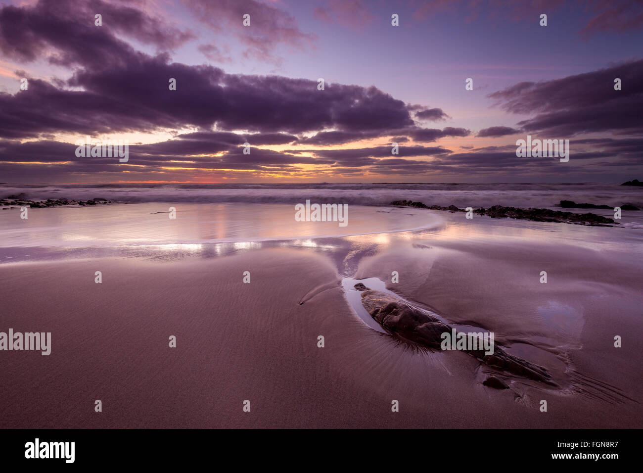 Sunset at Welcombe Mouth Beach in North Devon, UK. There is a blue and ...