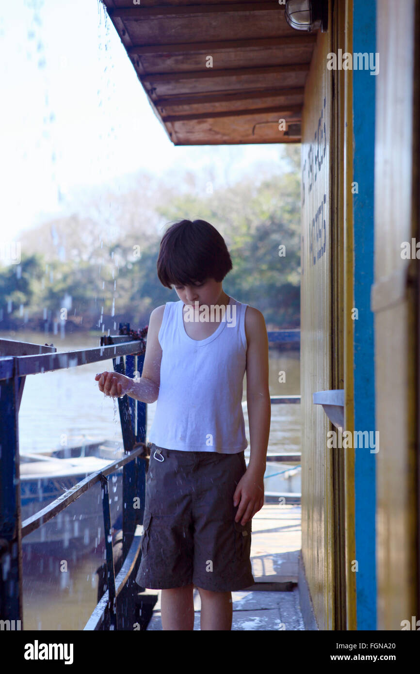 A young boy standing on a balcony in the rains Stock Photo - Alamy