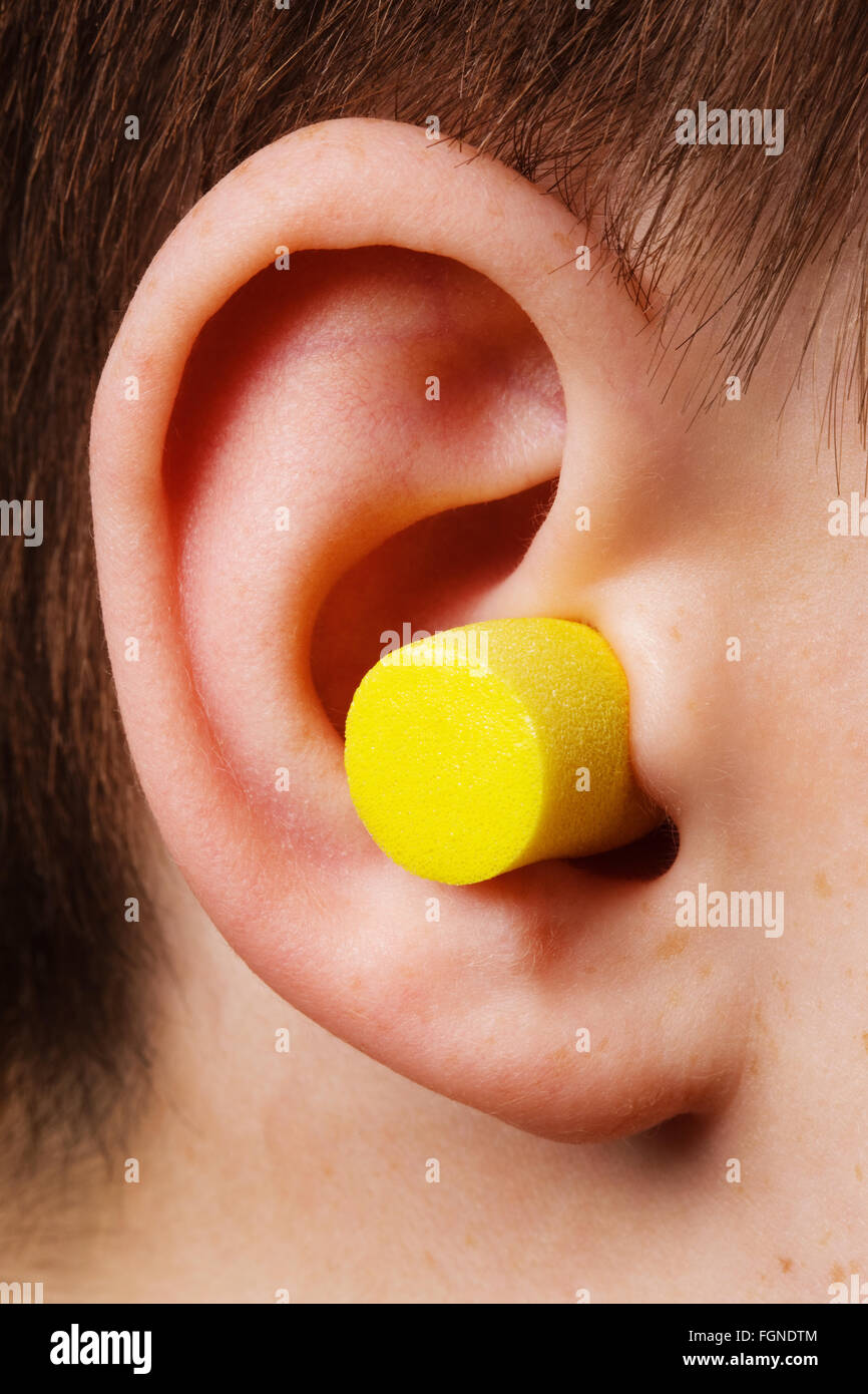 yellow earplug into the ear close up Stock Photo - Alamy