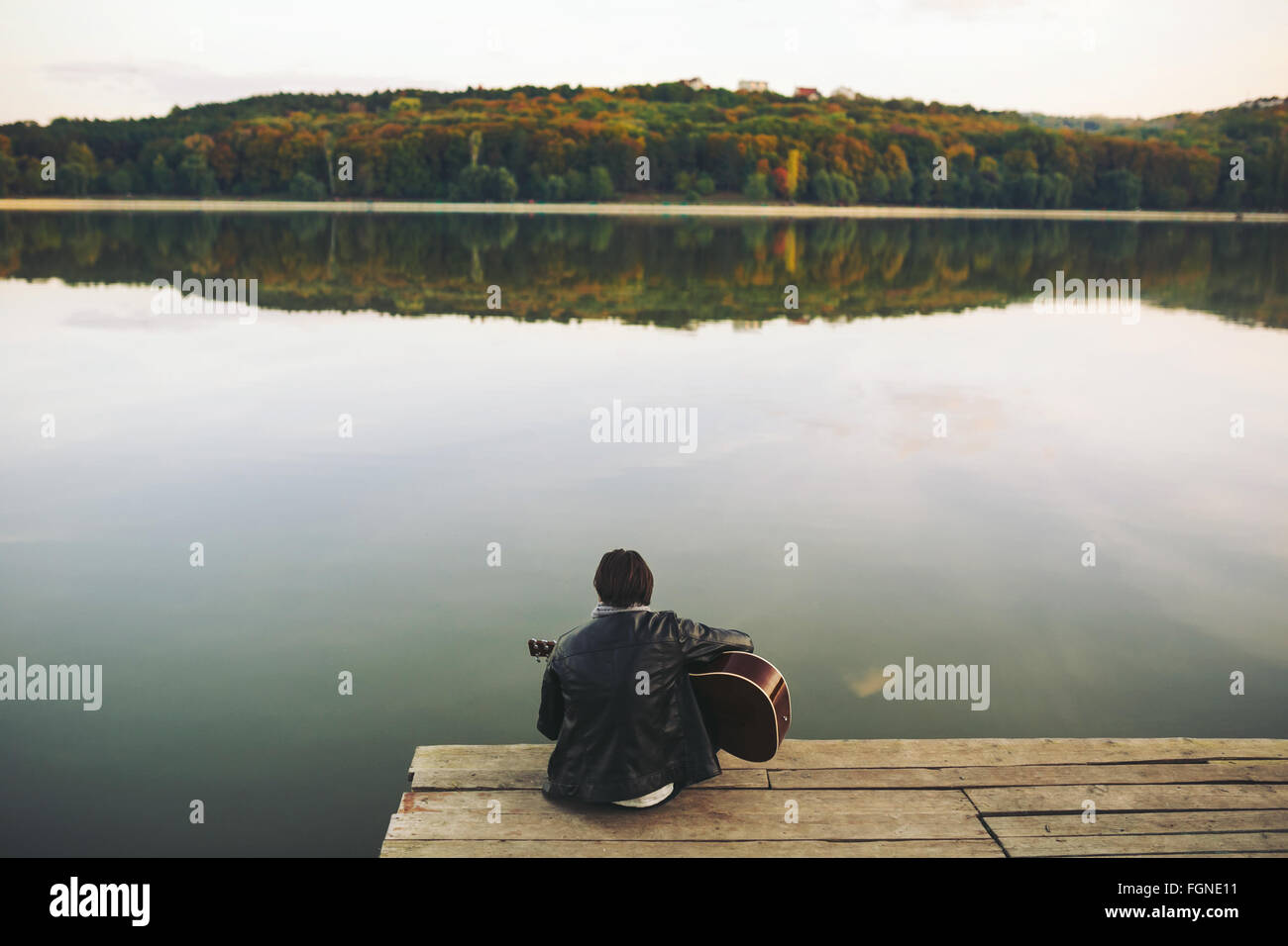Young man playing on guitar at the lake Stock Photo - Alamy