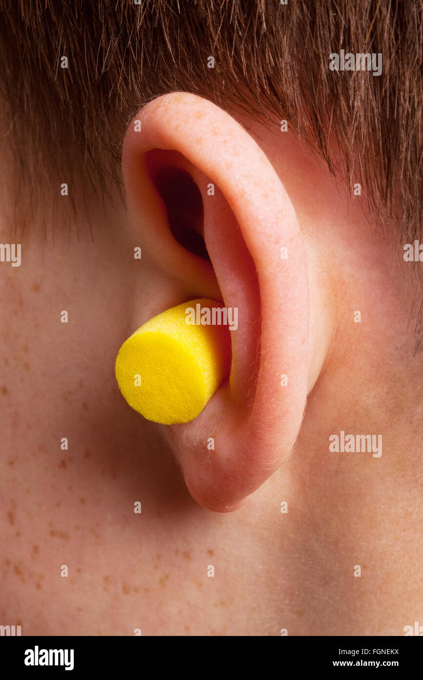 yellow earplug into the ear close up Stock Photo - Alamy