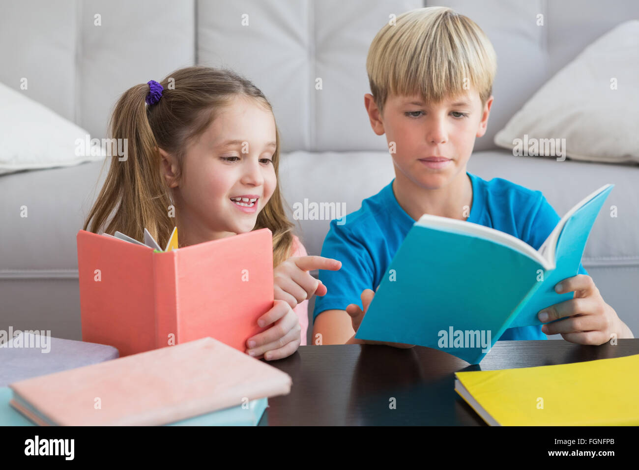 Happy siblings reading books on floor Stock Photo - Alamy
