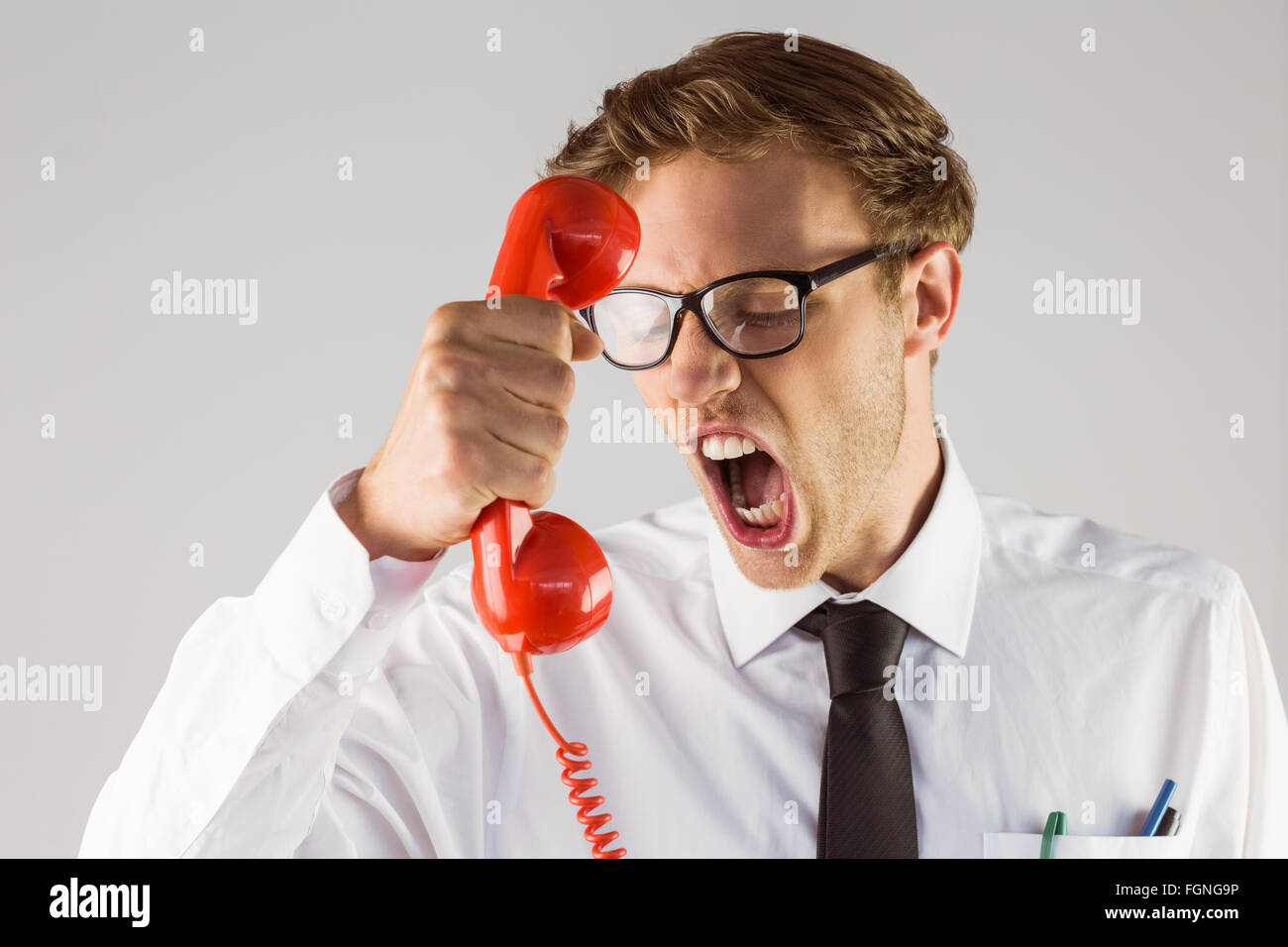 Angry geeky businessman holding telephone Stock Photo - Alamy