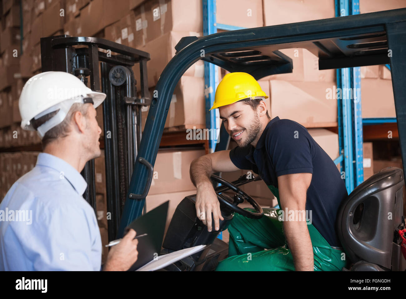 Warehouse manager talking with forklift driver Stock Photo - Alamy