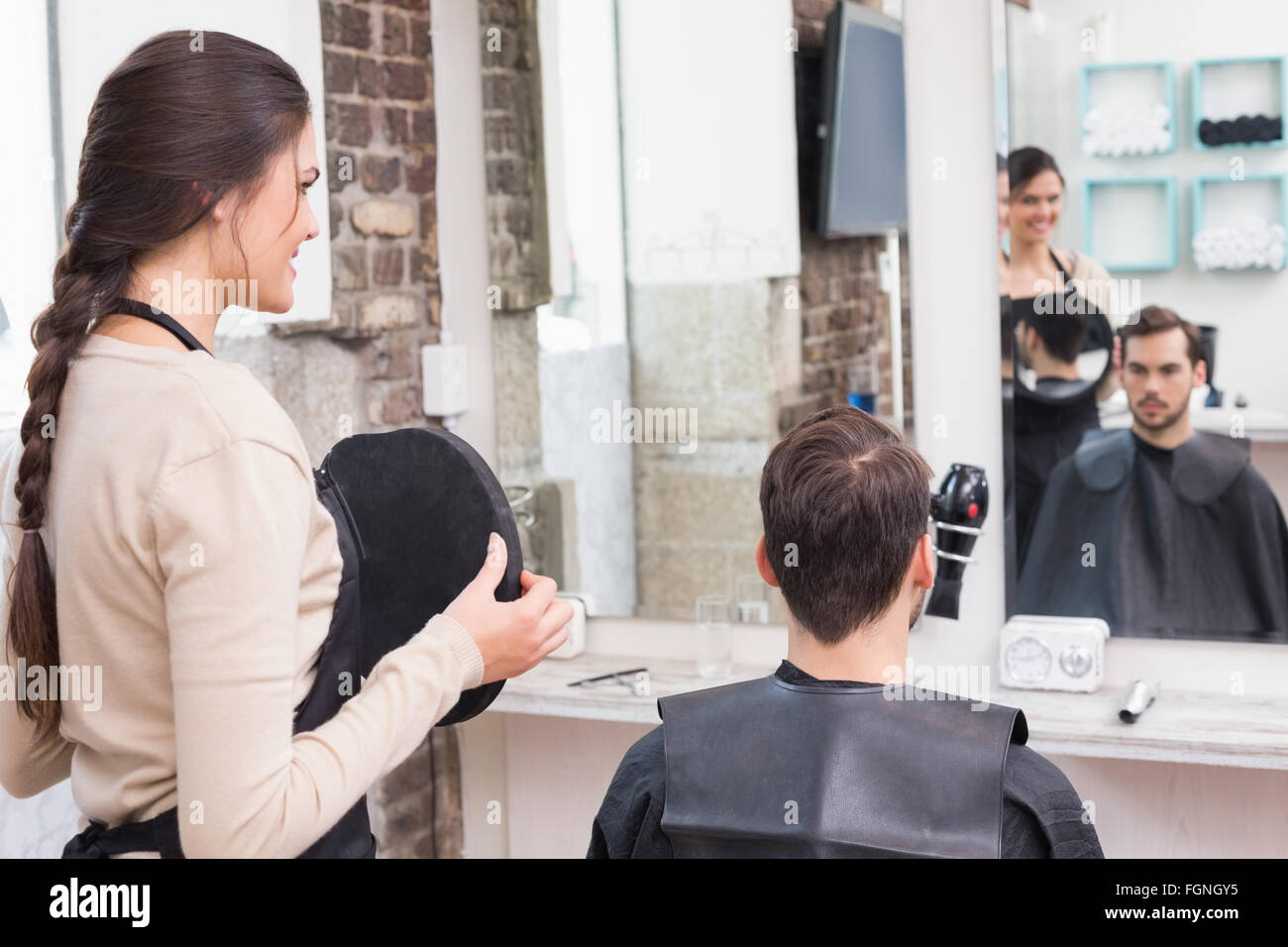 Pretty hair stylist showing man new haircut Stock Photo - Alamy