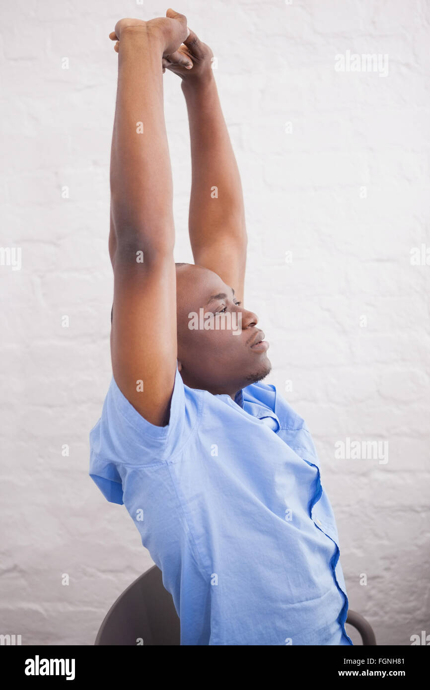 Businessman sitting with arms raised at desk Stock Photo - Alamy
