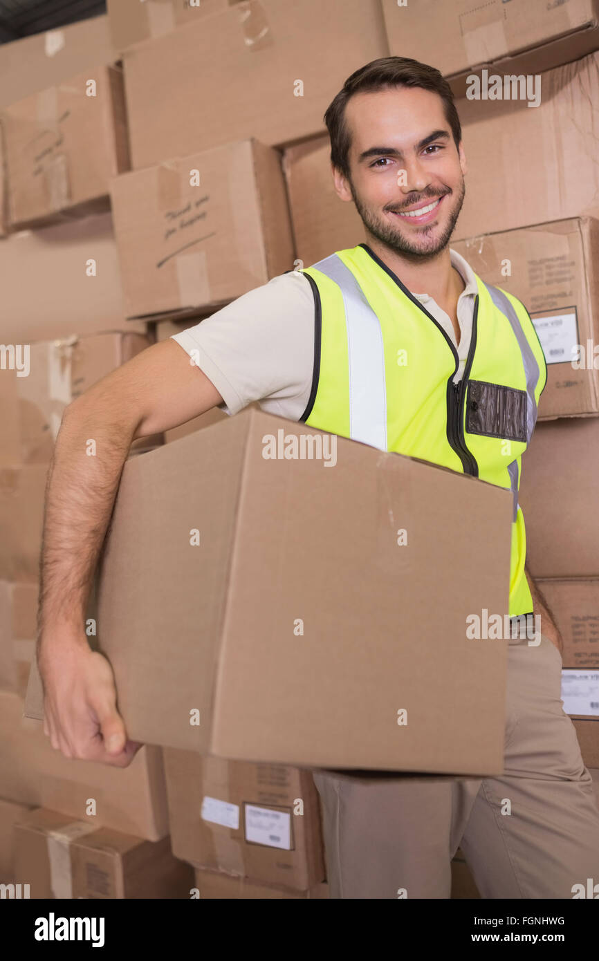 Worker carrying box in warehouse Stock Photo - Alamy