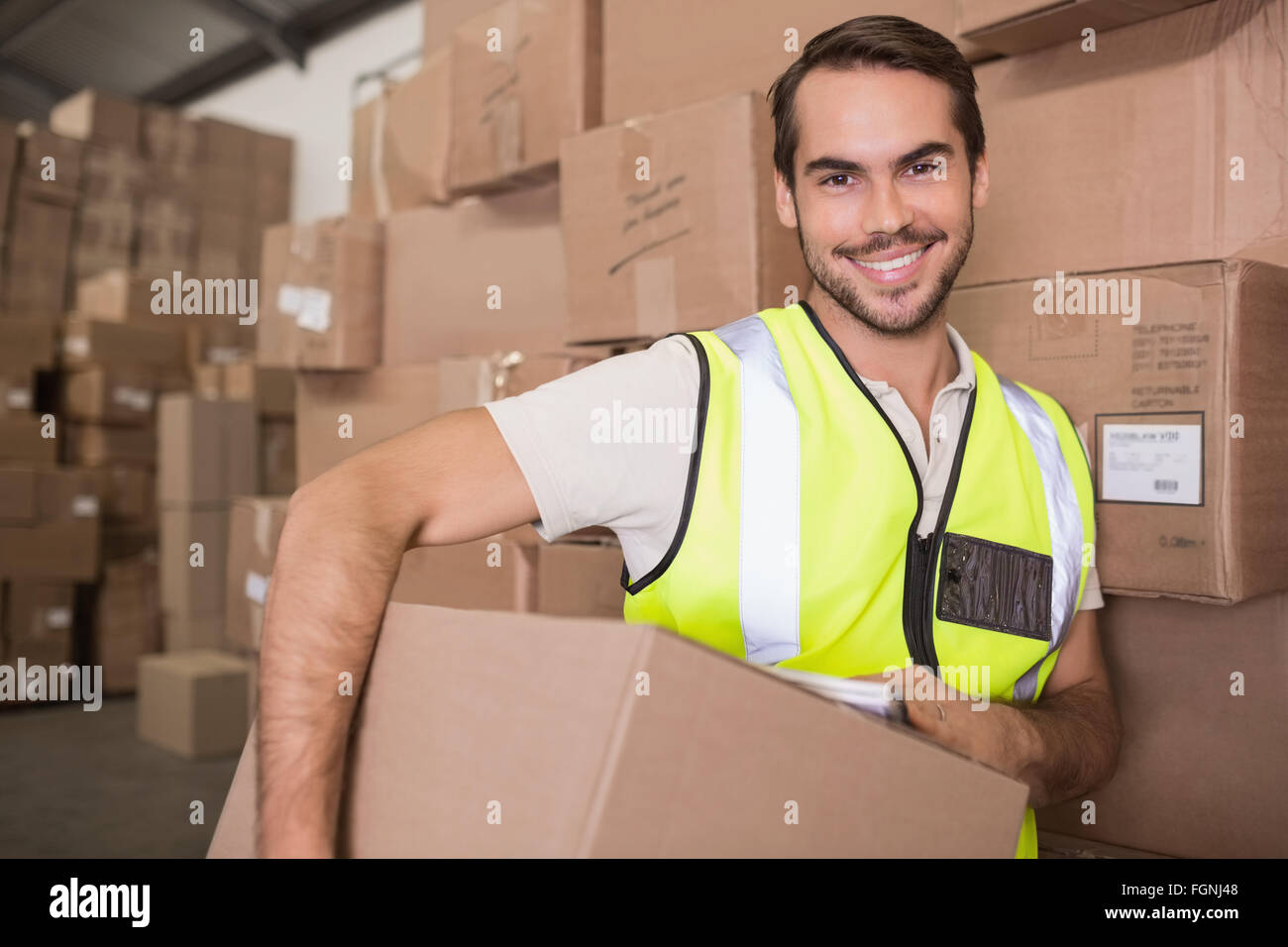 Worker carrying box in warehouse Stock Photo - Alamy