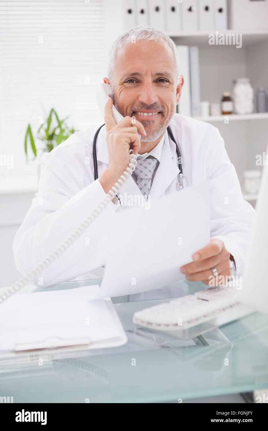Smiling doctor phoning and using computer Stock Photo - Alamy