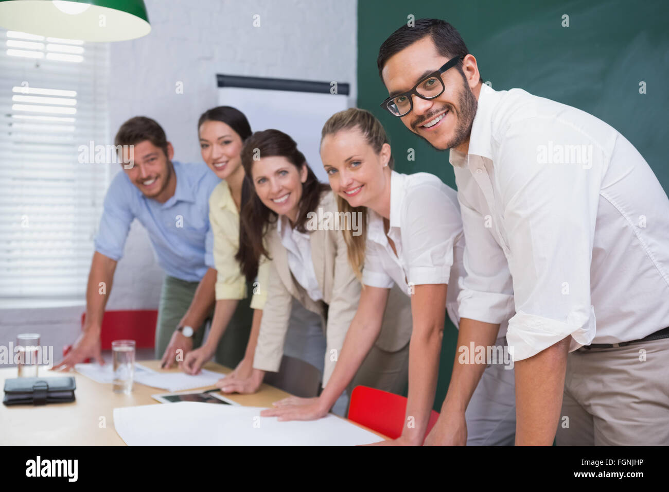 Architects going over blueprints and smiling at camera Stock Photo - Alamy